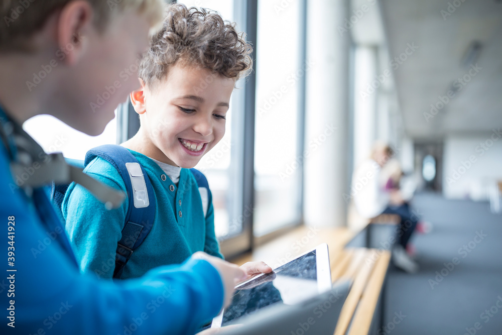 Smiling pupils sharing a tablet on school corridor Stock Photo | Adobe ... Smiling pupils sharing a tablet on school corridor Stock Photo | Adobe ...