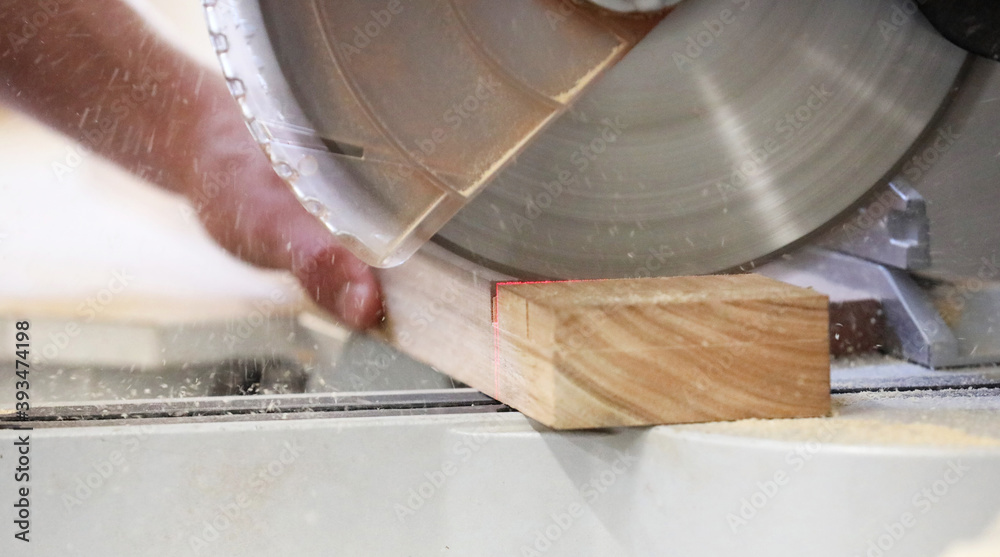 Hand holding a raw piece of timber being sawn by a fast cutting ...