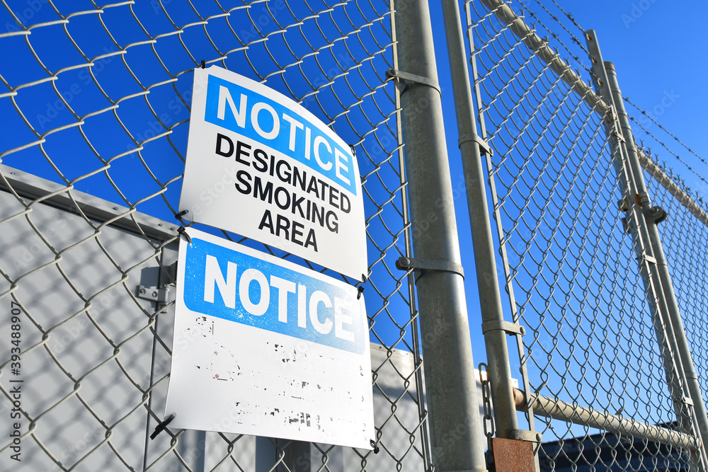 An image of a blue and white designated smoking area sign posted to a ...