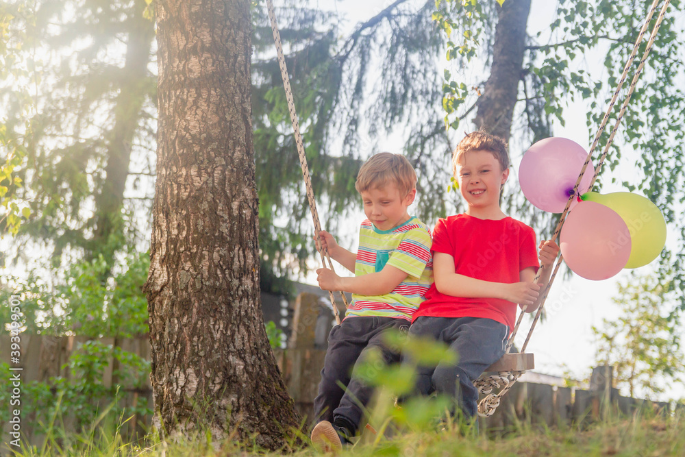 Two European boy swinging on a swing in the summer. Happy children ...