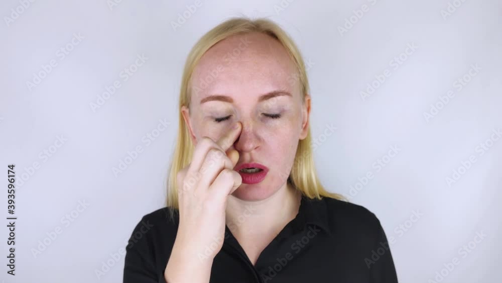 Nasal bridge pain, headache. A woman holds his nose with his hand and ...