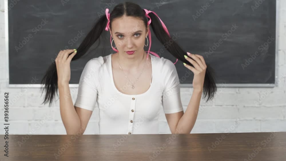 During school lessons, the student improves her hair and her image. Her ...
