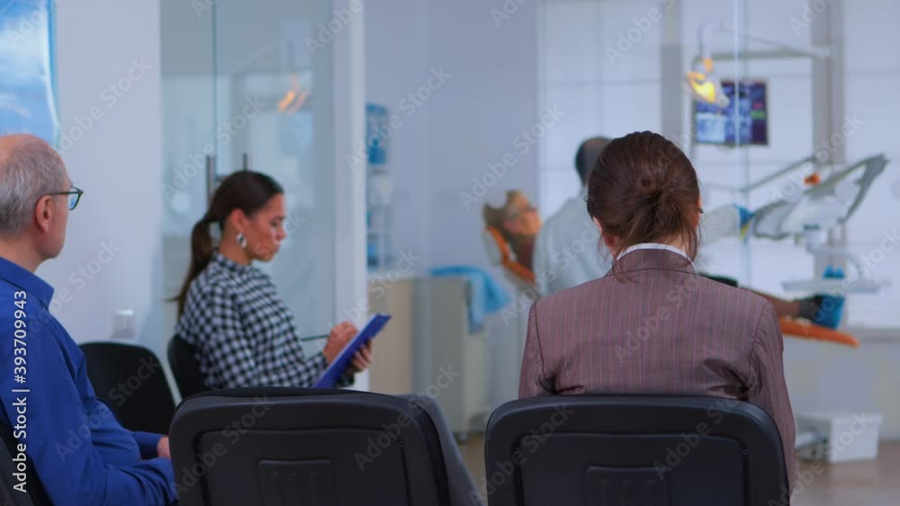 Back view of woman filling in dental form sitting on chiar in waiting ...