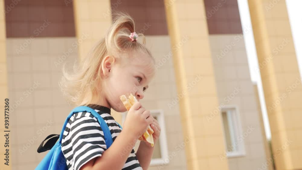 schoolgirl eating a sandwich during recess in school. kids education ...