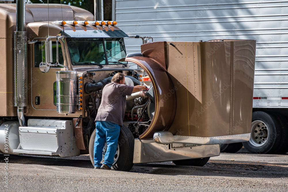 Truck driver checks the correct operation of the engine of a brown big ...