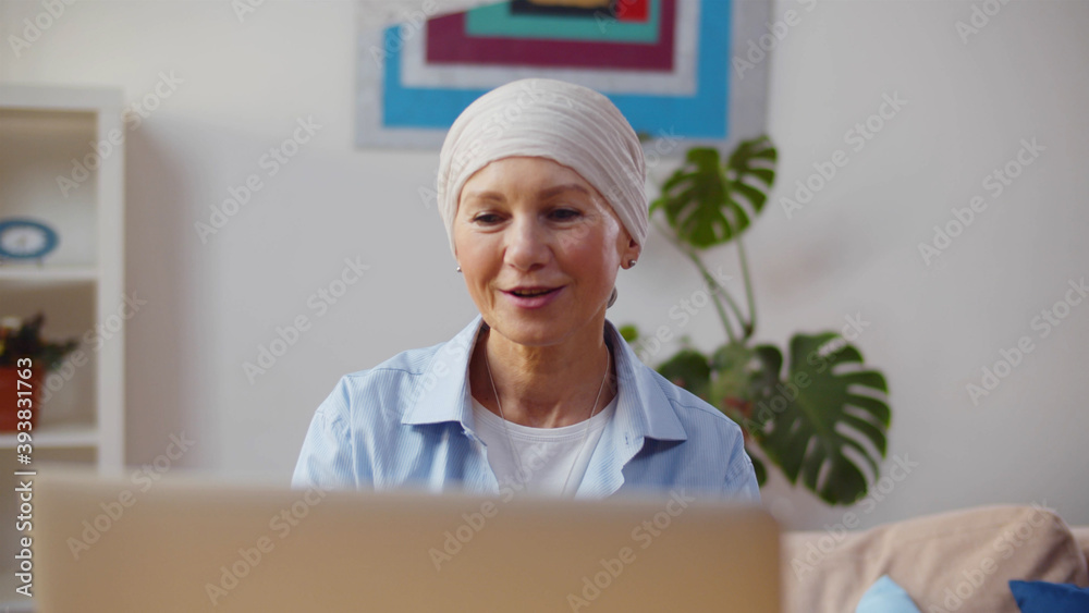 Portrait of senior woman having cancer using laptop sitting in modern ...