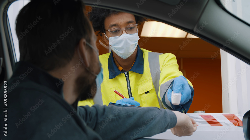 African worker wearing safety mask in car check point booth scanning ...