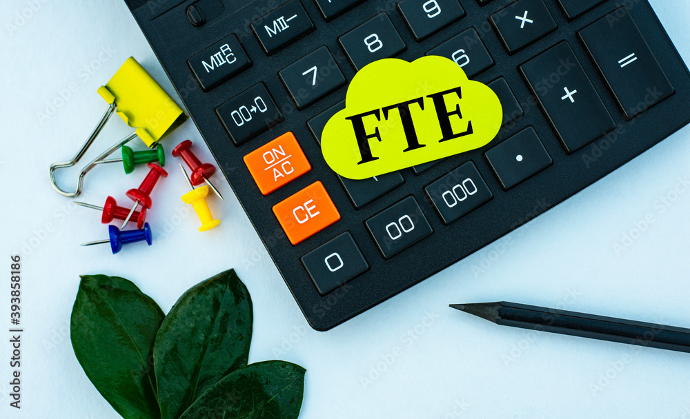 FTE - word on yellow note sheet on white background with calculator ...