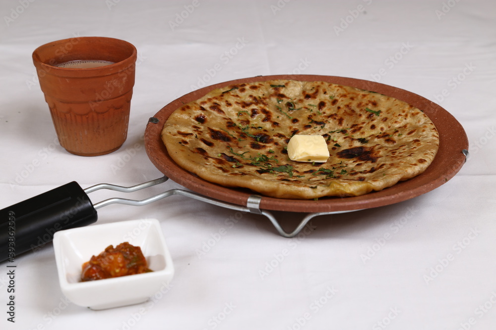 Hot Aloo Paratha on Tawa with butter, tea, and pickle. Stock Photo ...