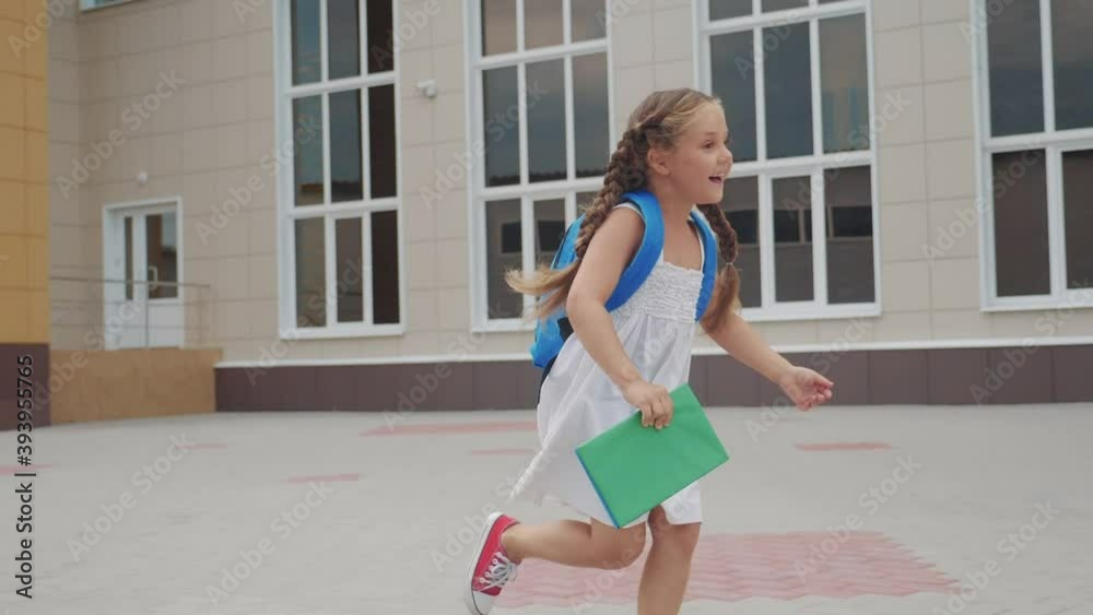 little girl kid with backpack and a textbook runs fun in hurrying to ...