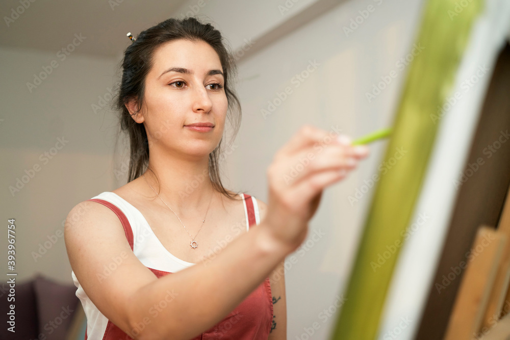 Woman posing for camera while painting oil painting. Artist posing with ...