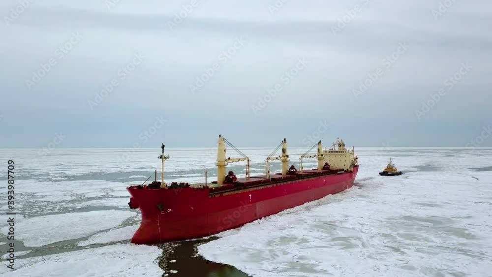Aerial above epic huge steel ship breaks ice by bow of ship and floats ...