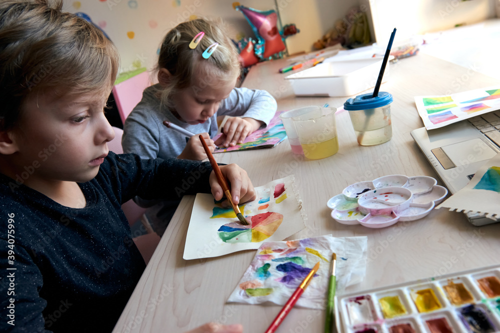 Children painting pictures with watercolor paints during art lesson ...