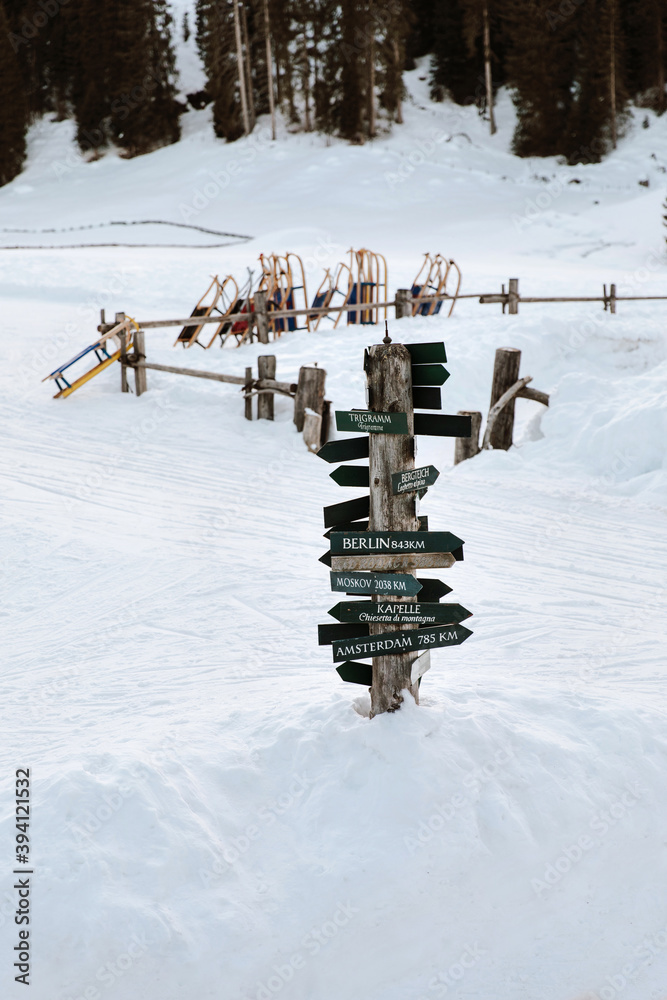 Directional road signs tower standing in the snow in front of sleds ...