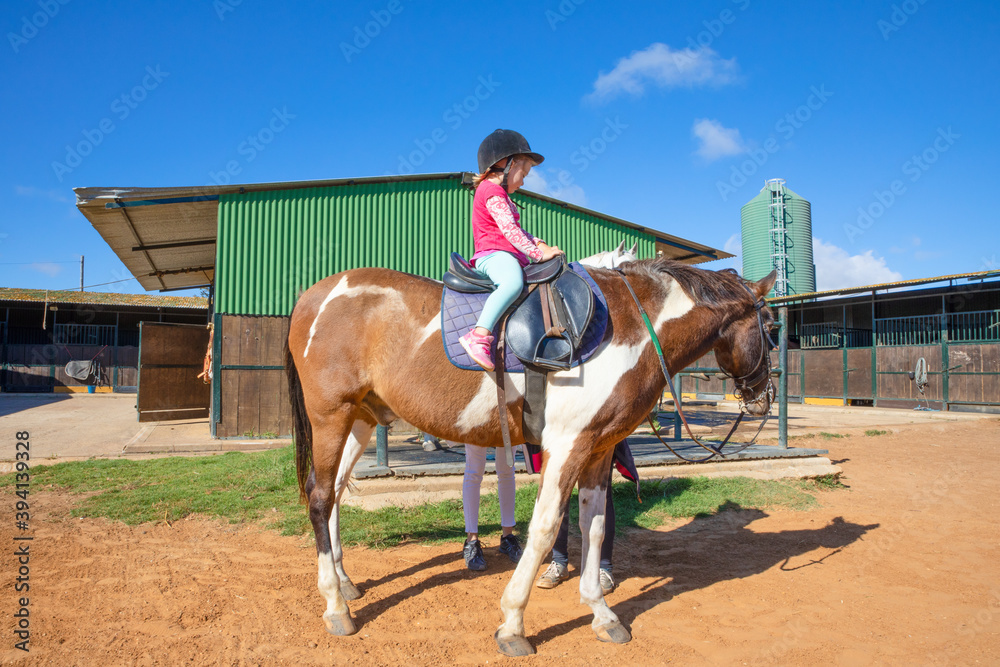 side view of little girl sitting on a horse in a riding center Stock ...