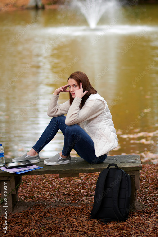 Beautiful young college student sits alone on campus in fall leaves ...