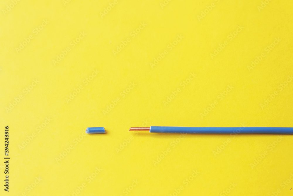 Blue electrical wire stripped of insulation on one side on a yellow ...