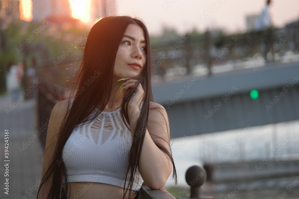 Regretful asian girl posing in sunset time on embankment looking away ...