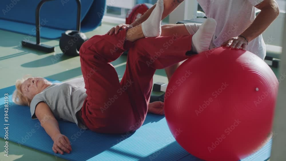 Medical worker assisting mature female patient performing stretching ...