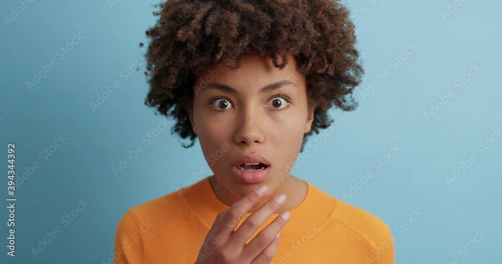 Stunned dark skinned woman looks impressed at camera stares bugged eyes ...