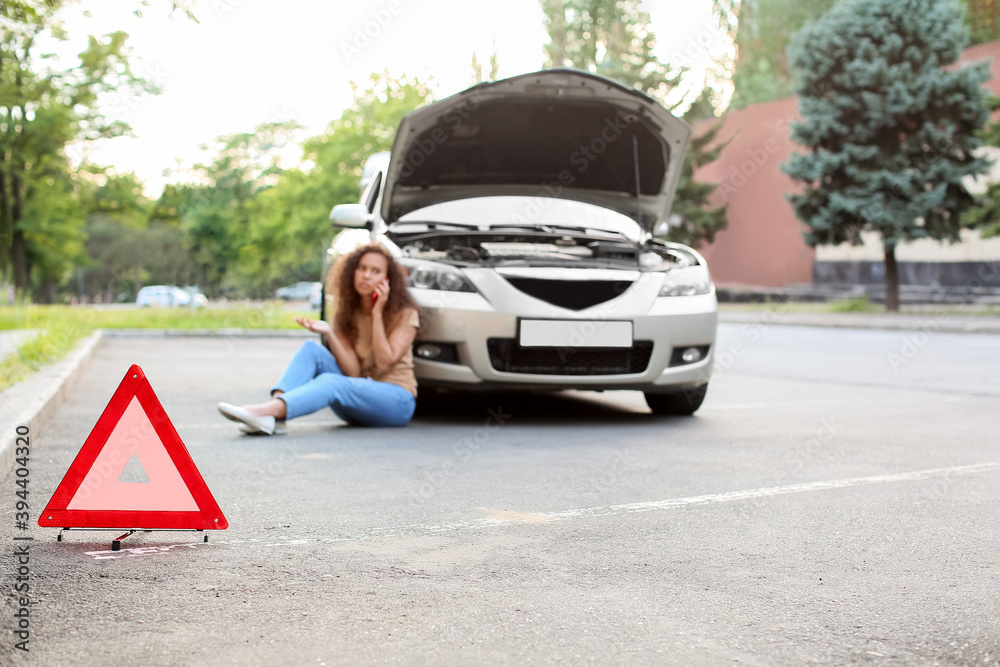 Emergency stop sign and stressed African-American woman near broken car ...