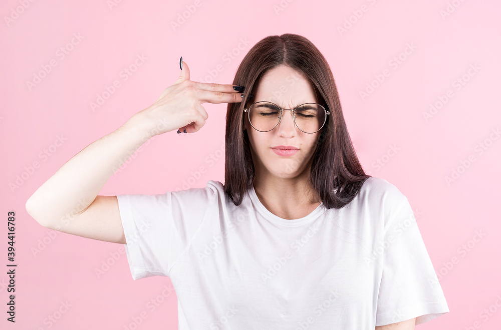 Young girl directs hand in the form of a pistol to her head on a pink ...