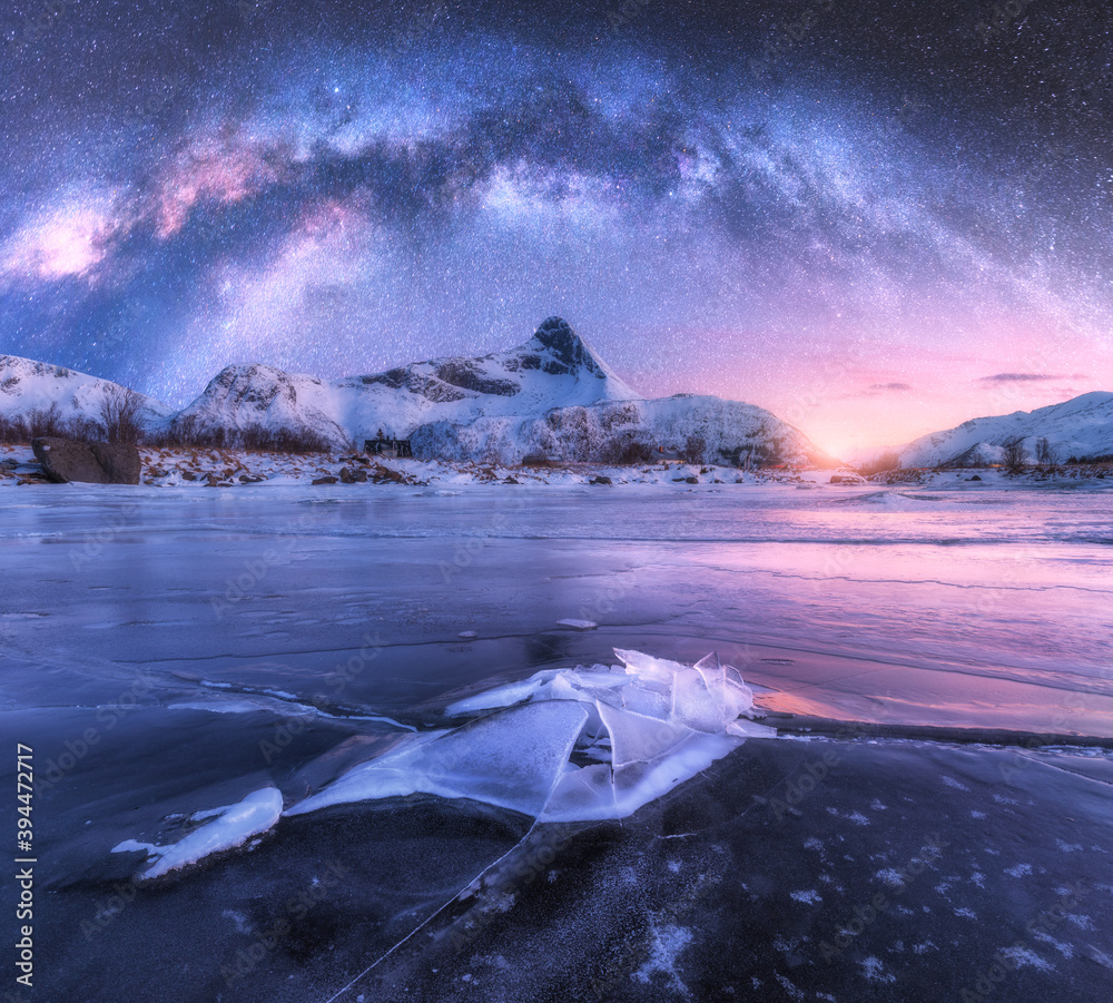 Milky Way above frozen sea coast and snow covered mountains in winter ...