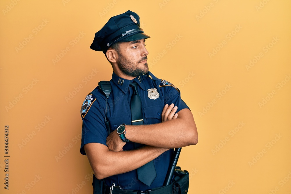 Handsome hispanic man wearing police uniform looking to the side with ...