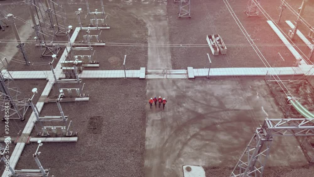 Group of workers in uniform walks on territory to check electrical ...