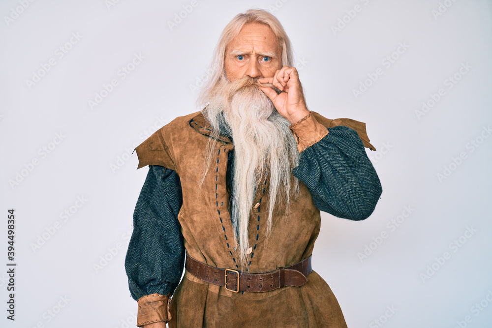 Old senior man with grey hair and long beard wearing viking traditional ...