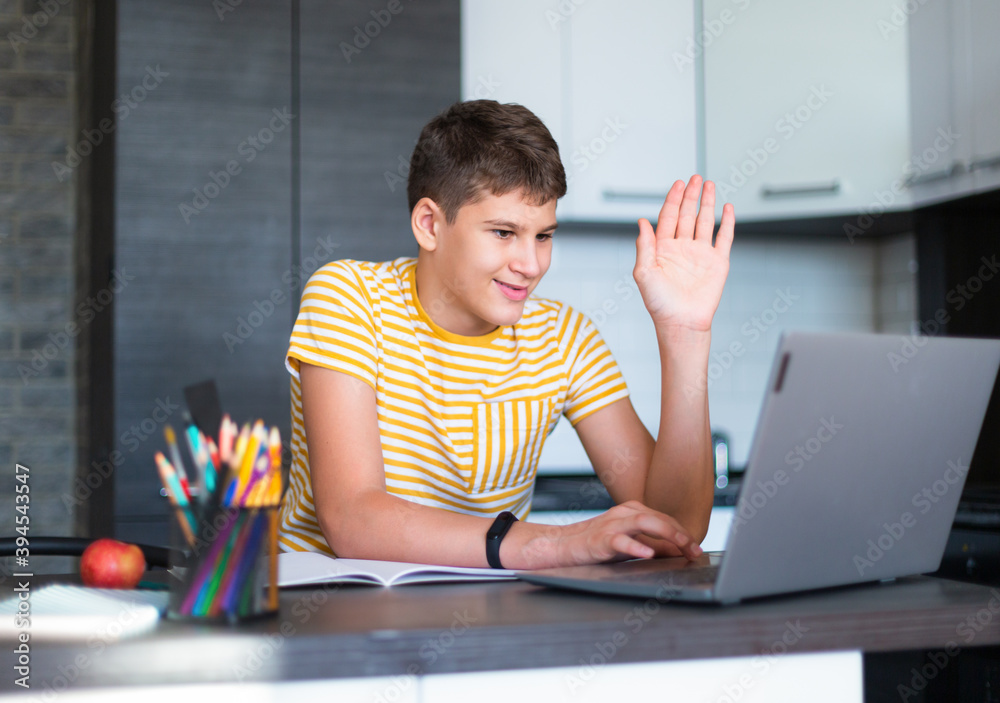 Cute young teenager in yellow shirt sitting behind desk in kitchen next ...
