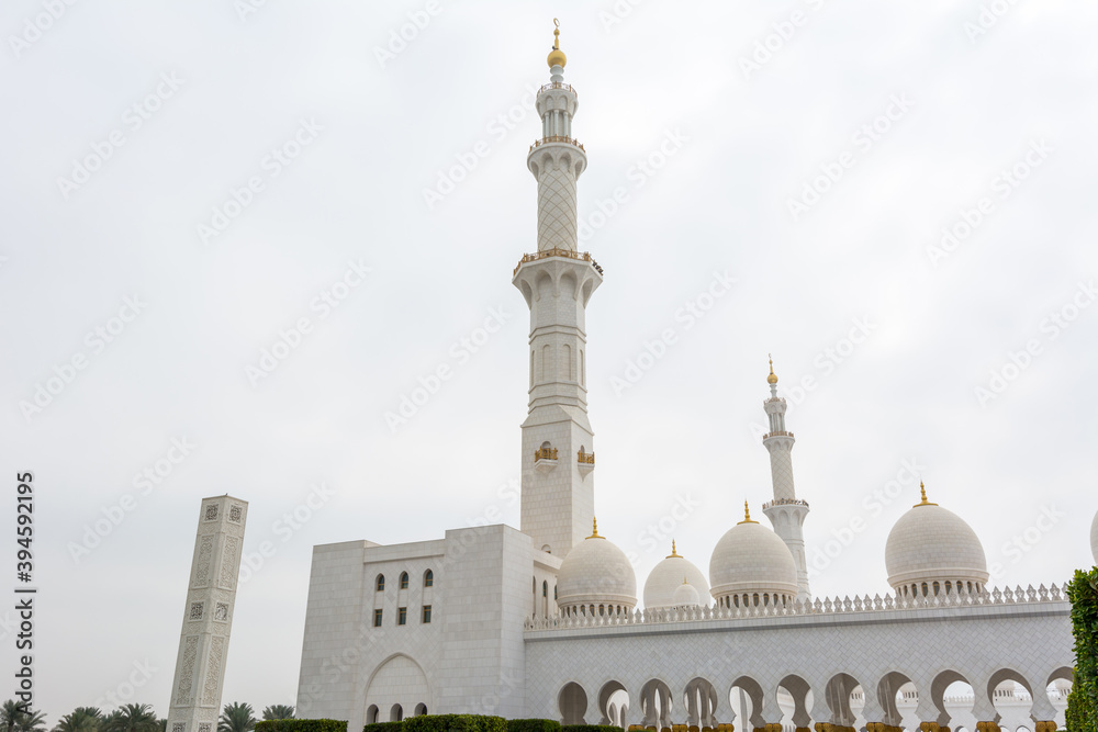 Minaret and domes of white Grand Mosque against white cloudy sky, also ...