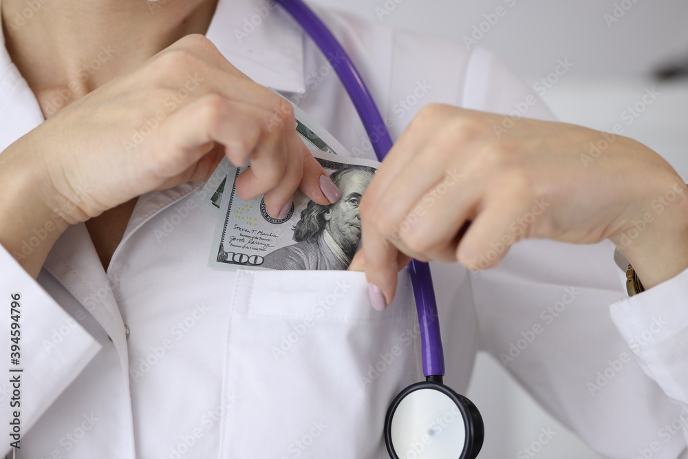 Doctor puting dollar bill in uniform pocket at clinic closeup ...
