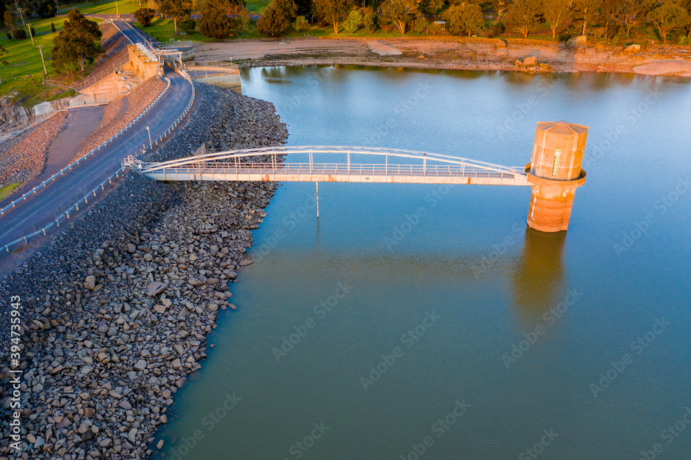 Aerial view of a water tower in a reservoir connected to the dam wall ...