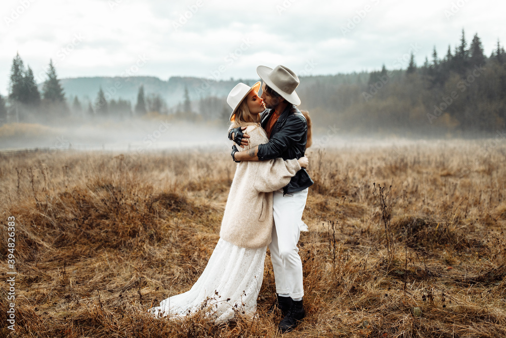 Lovely couple posing at the field, attractive bride hug handsome groom ...