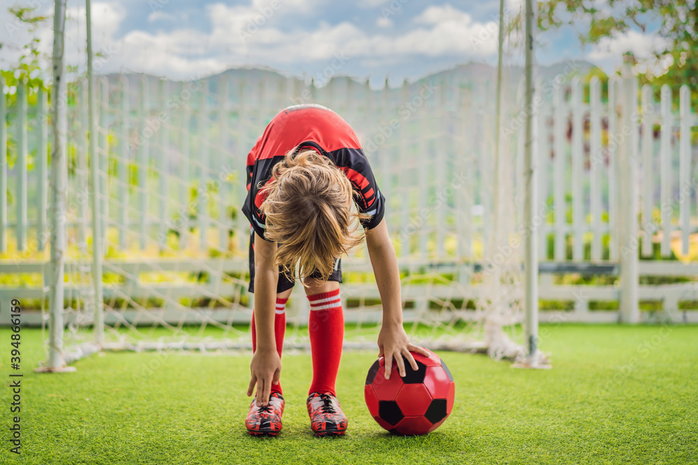 Little cute kid boy in red football uniform playing soccer, football on ...