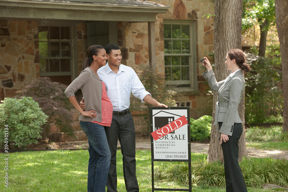 Realtor taking picture of couple next to house sold sign Stock Photo ...