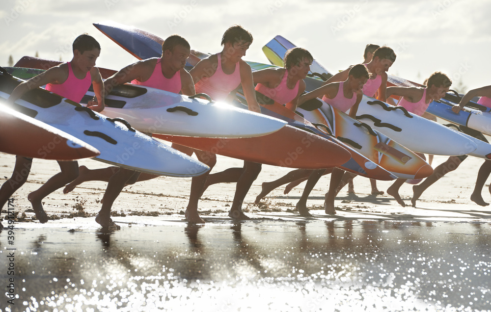 Foto de Team of male surf lifeguards training and running into sea ...