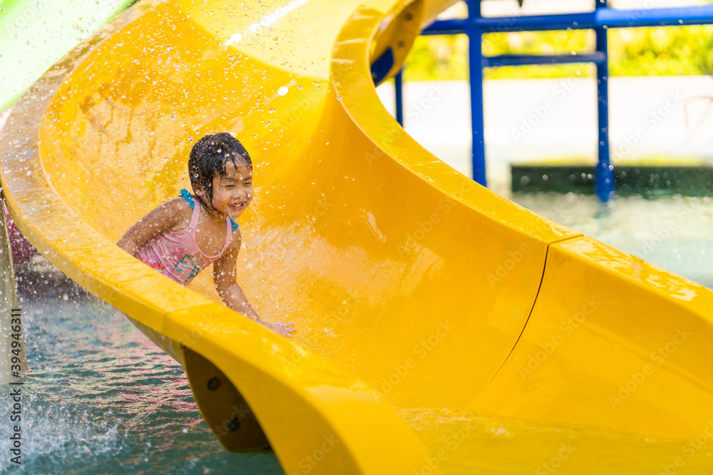 Cute little girl in swimming suit playing waterslide at waterpark ...