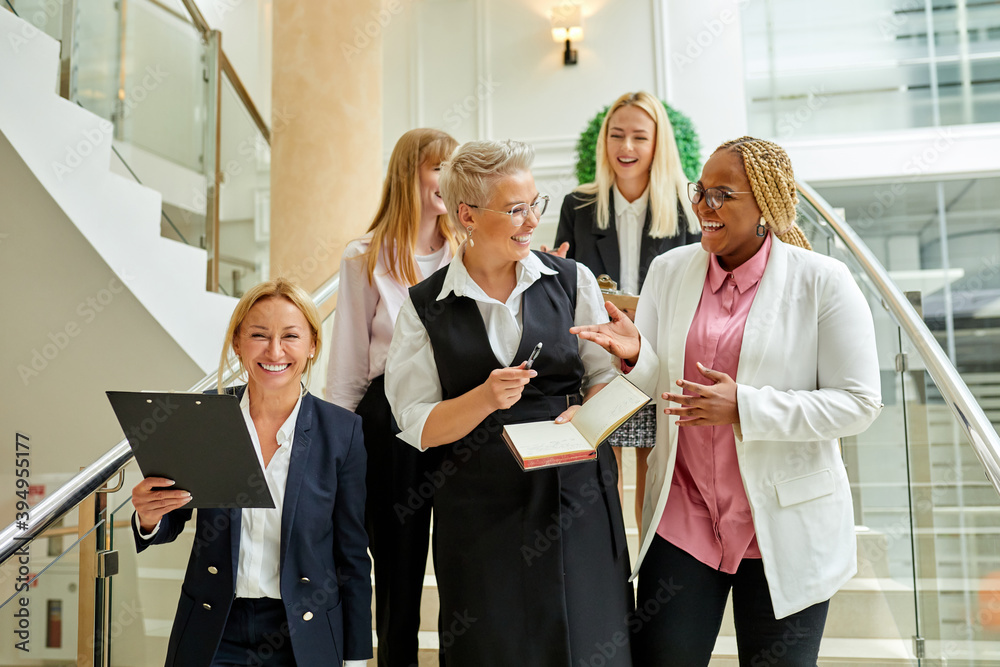 team of diverse women colleagues on stairs talking, discussing business ...