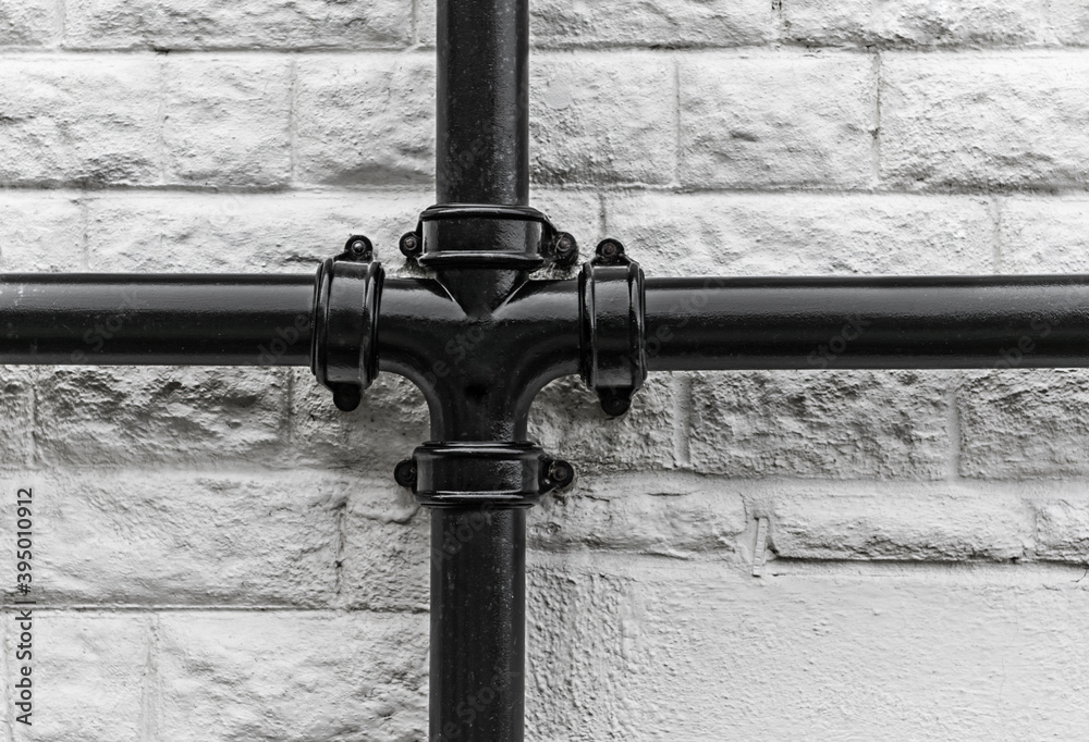 Old fashioned heavy cast iron black drainpipes against a white brick ...