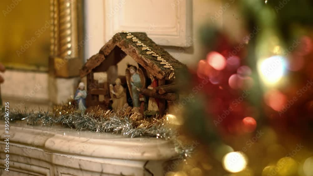 Woman puts miniature figurines of Mary in a christmas crib above the ...