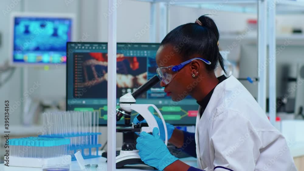 African woman biochemist using microscope in modern equipped laboratory ...