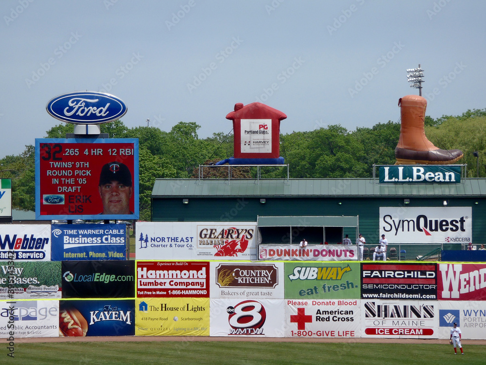 Baseball player stands in the outfield with ads on wall including LL ...