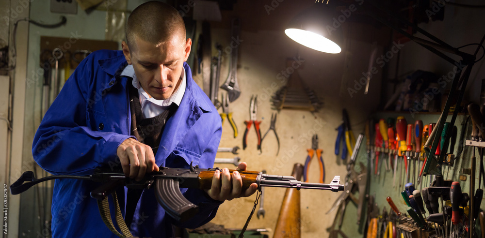Gunsmith with Kalashnikov assault rifle in a weapons workshop Stock ...