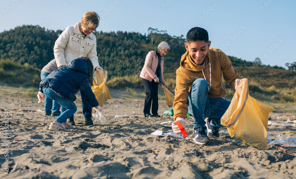 Young man picking up trash with group of volunteers on the beach Stock ... Young man picking up trash with group of volunteers on the beach Stock ...