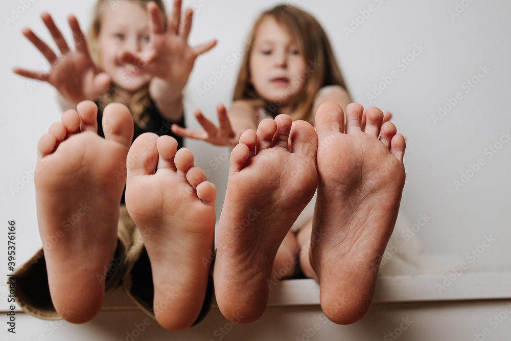 Brother and sister holding bare feet close up to the camera. Their ...