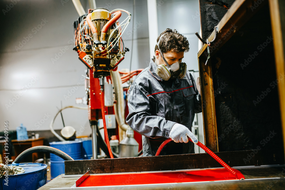 An industrial worker produces a rubber blank, pours liquid into a mold ...