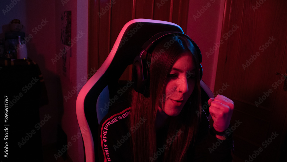 Gamer girl wins the game and celebrates her triumph by raising her fist ...