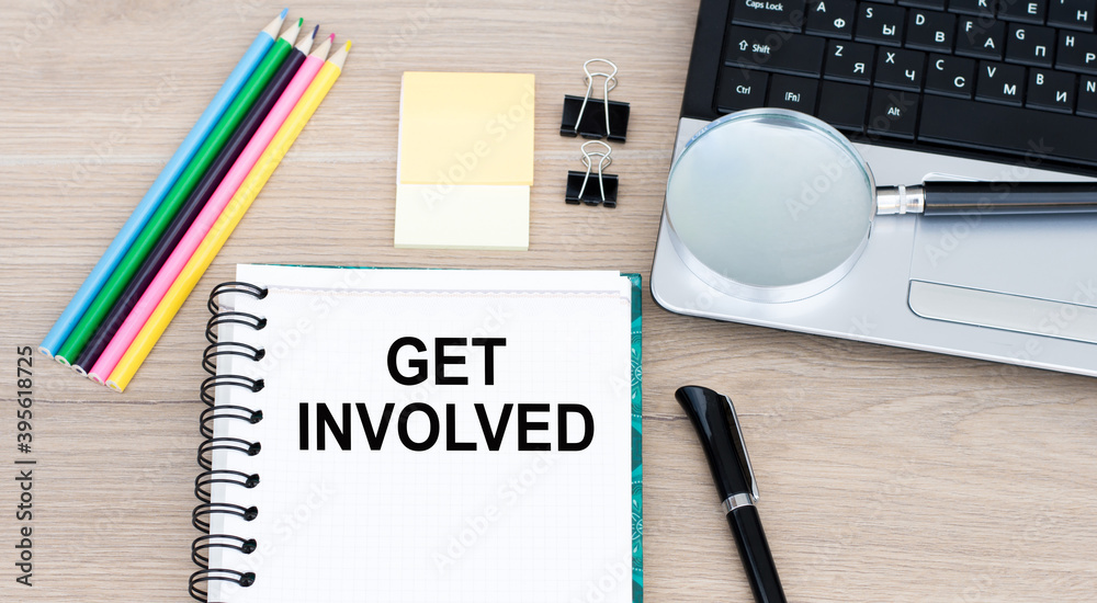 Text GET INVOLVED on an open notebook on an office table, next to a ...